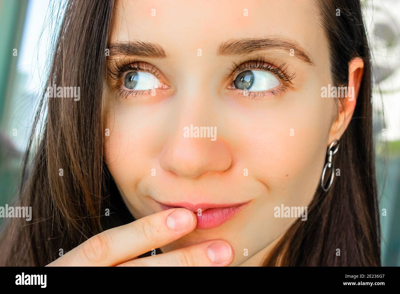 Curious surprised sly pretty girl with dark hair and gray eyes looks ...