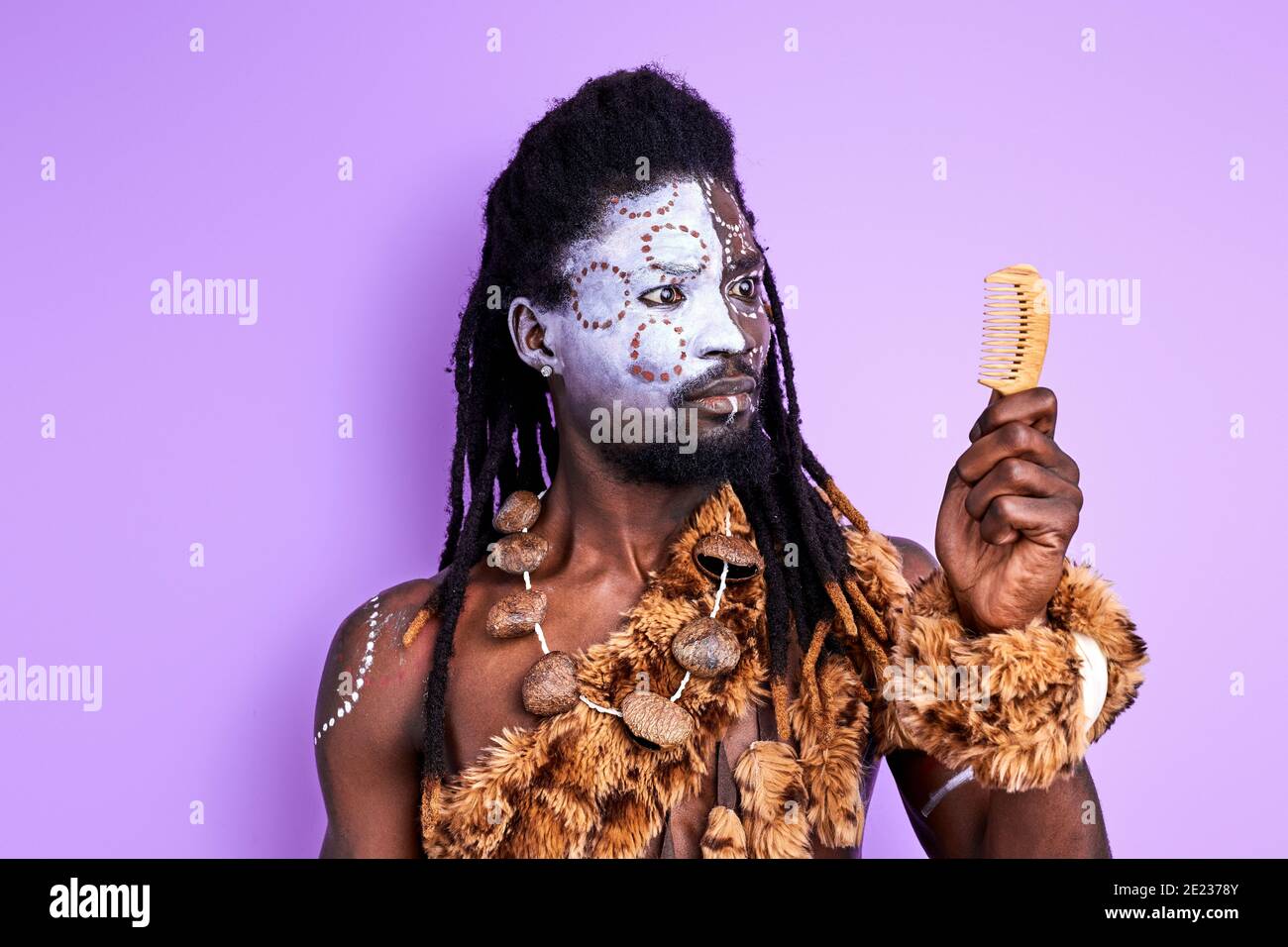 tribal primitive male looks at comb, he doesn't know how to use it ...