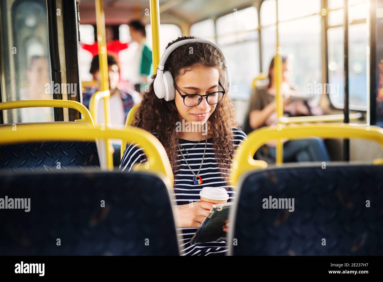 Beautiful girl with curly hair is sitting alone in a bus a listening to ...