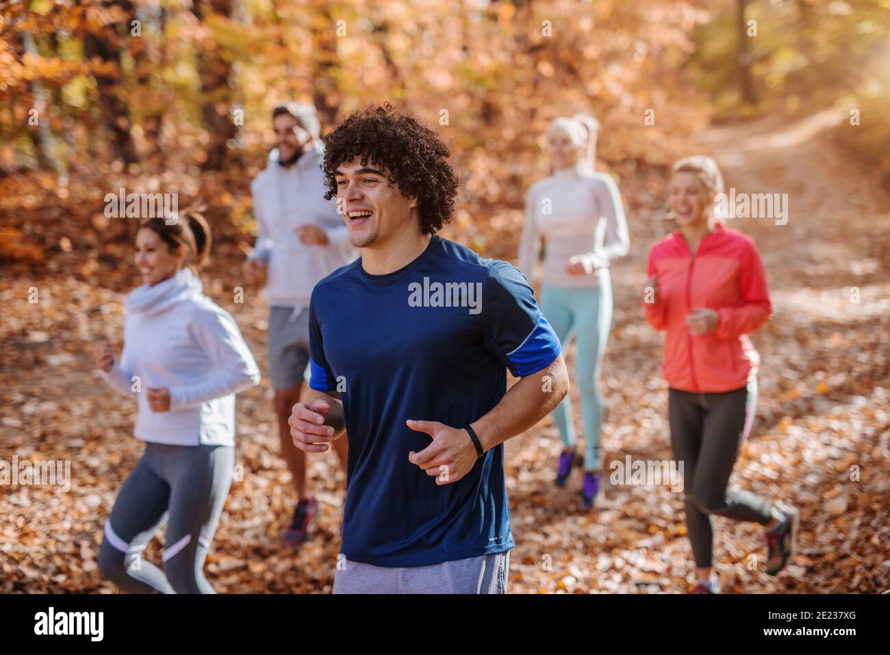 Organized small group of people running in woods in autumn Stock Photo ...