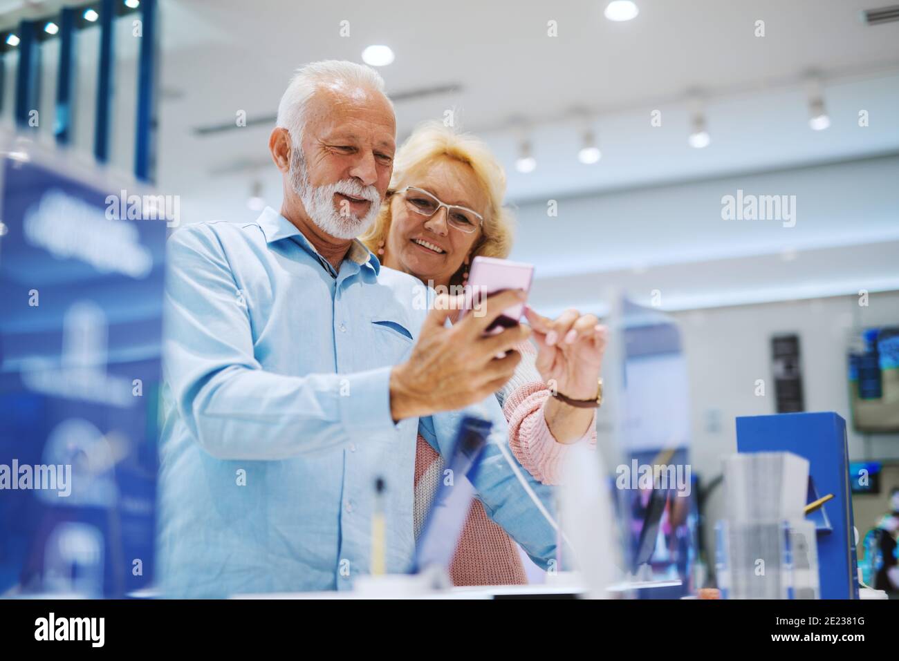 Senior couple choosing smart phone. Tech store interior Stock Photo - Alamy