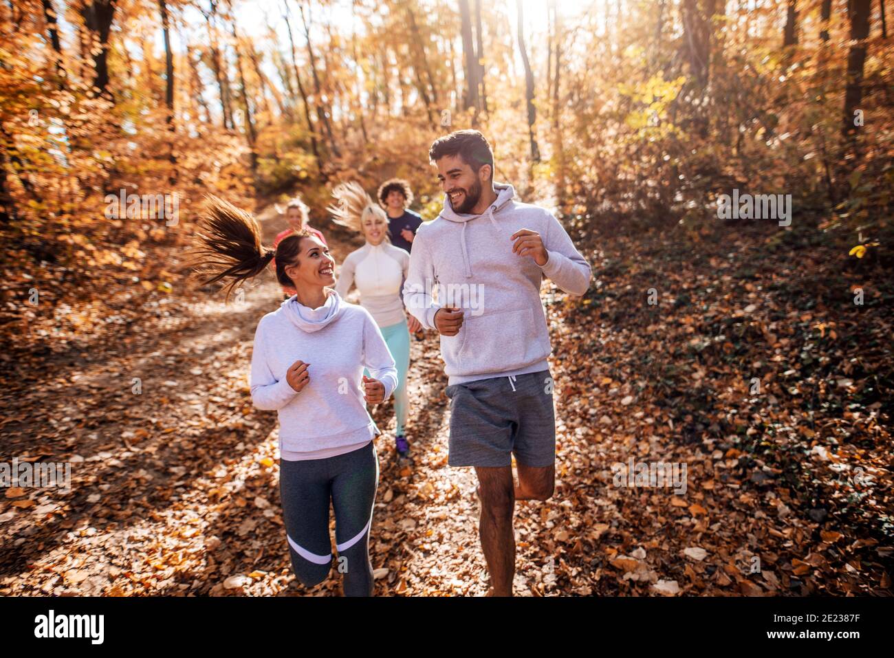 Organized small group of people running in woods in autumn Stock Photo ...