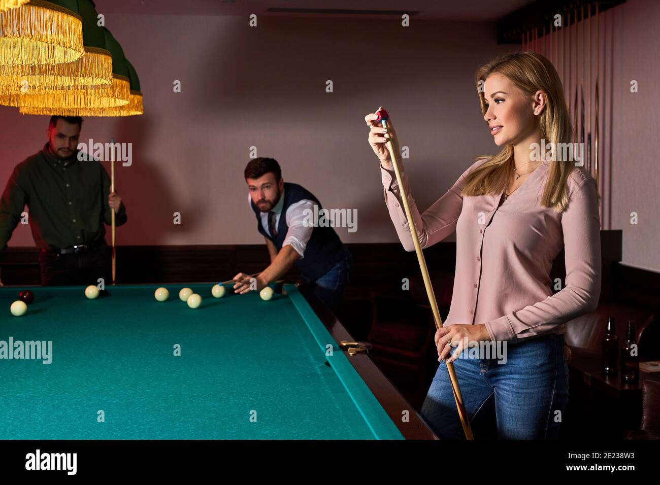 woman preparing to play professional billiards in the dark billiard club, spend pleasant time ...