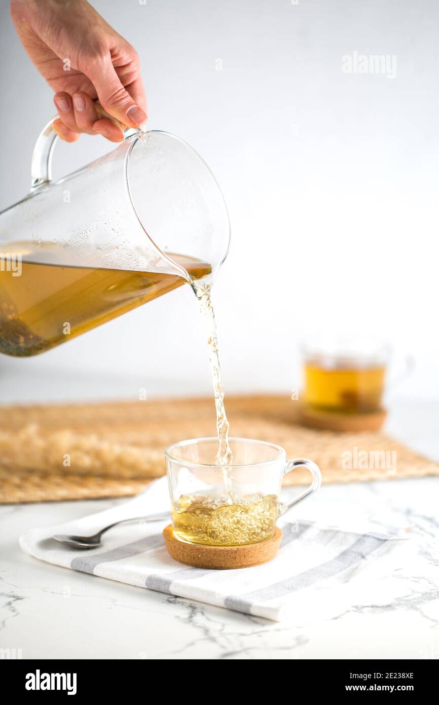 A cup of Green tea pouring from the teapot on the white background with ...