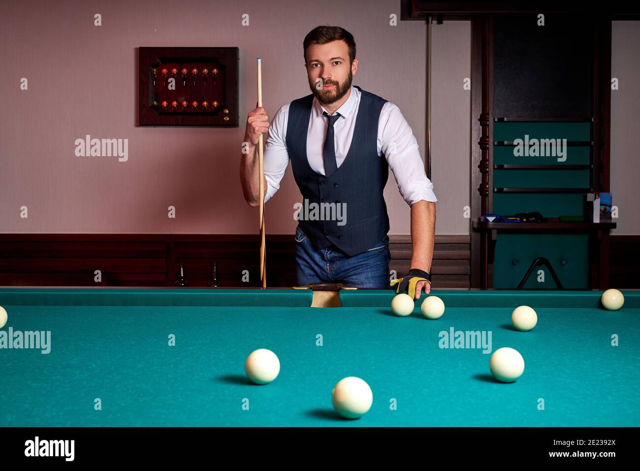 male standing near billiards table, playing snooker, looking at camera ...