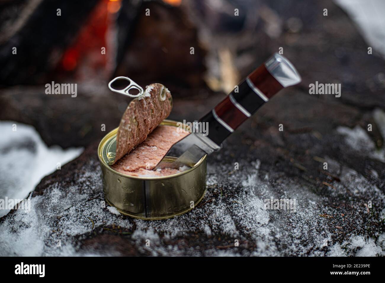 Open can of meat. Knife stuck inside. A burning fire Stock Photo - Alamy