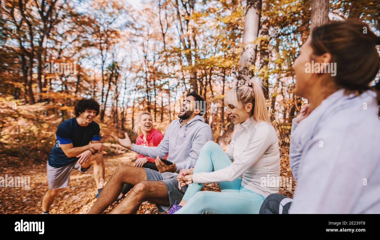 Group of runners sitting and chatting after running. Forest in autumn ...