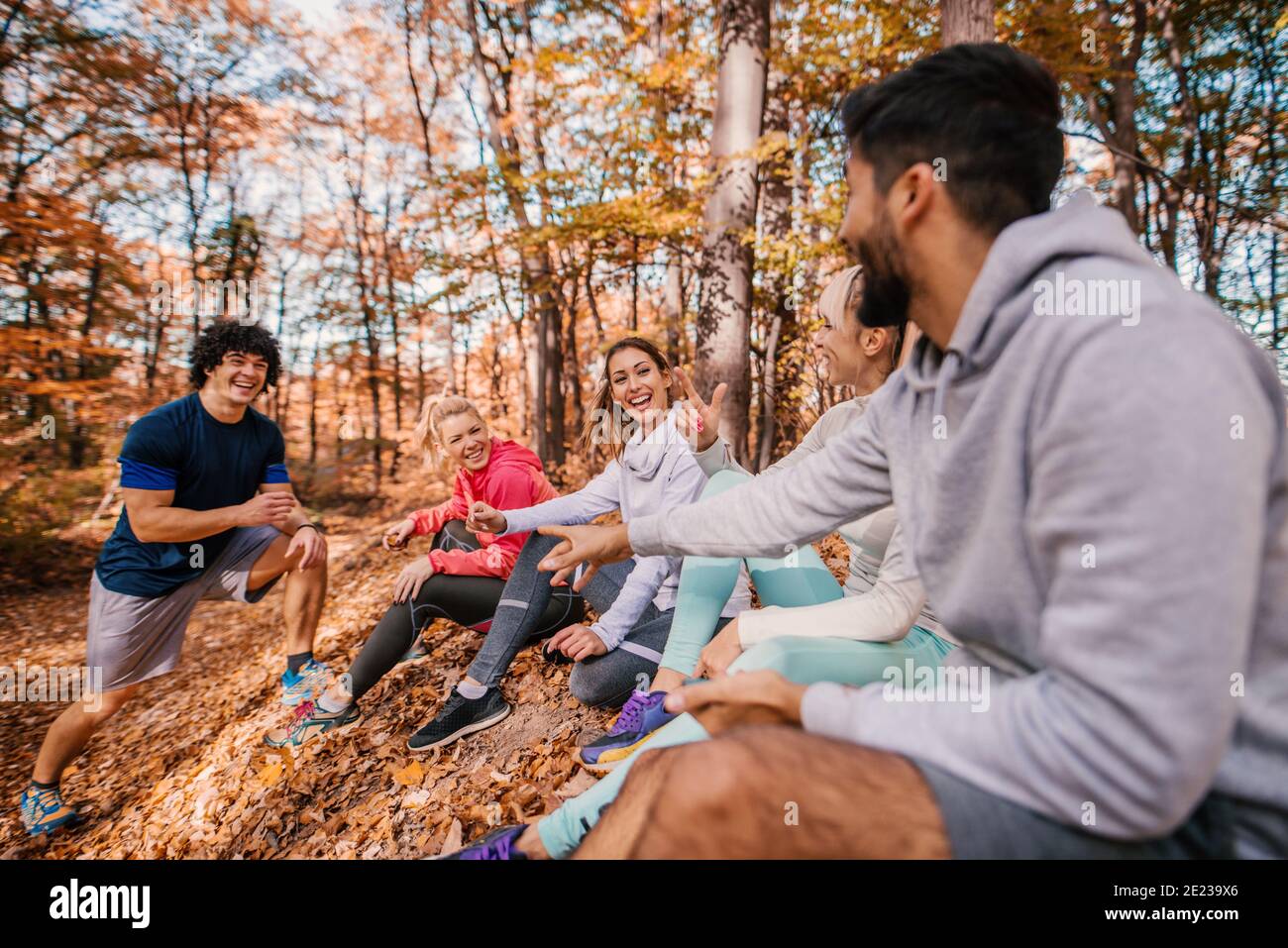 Group of runners sitting and chatting after running. Forest in autumn ...