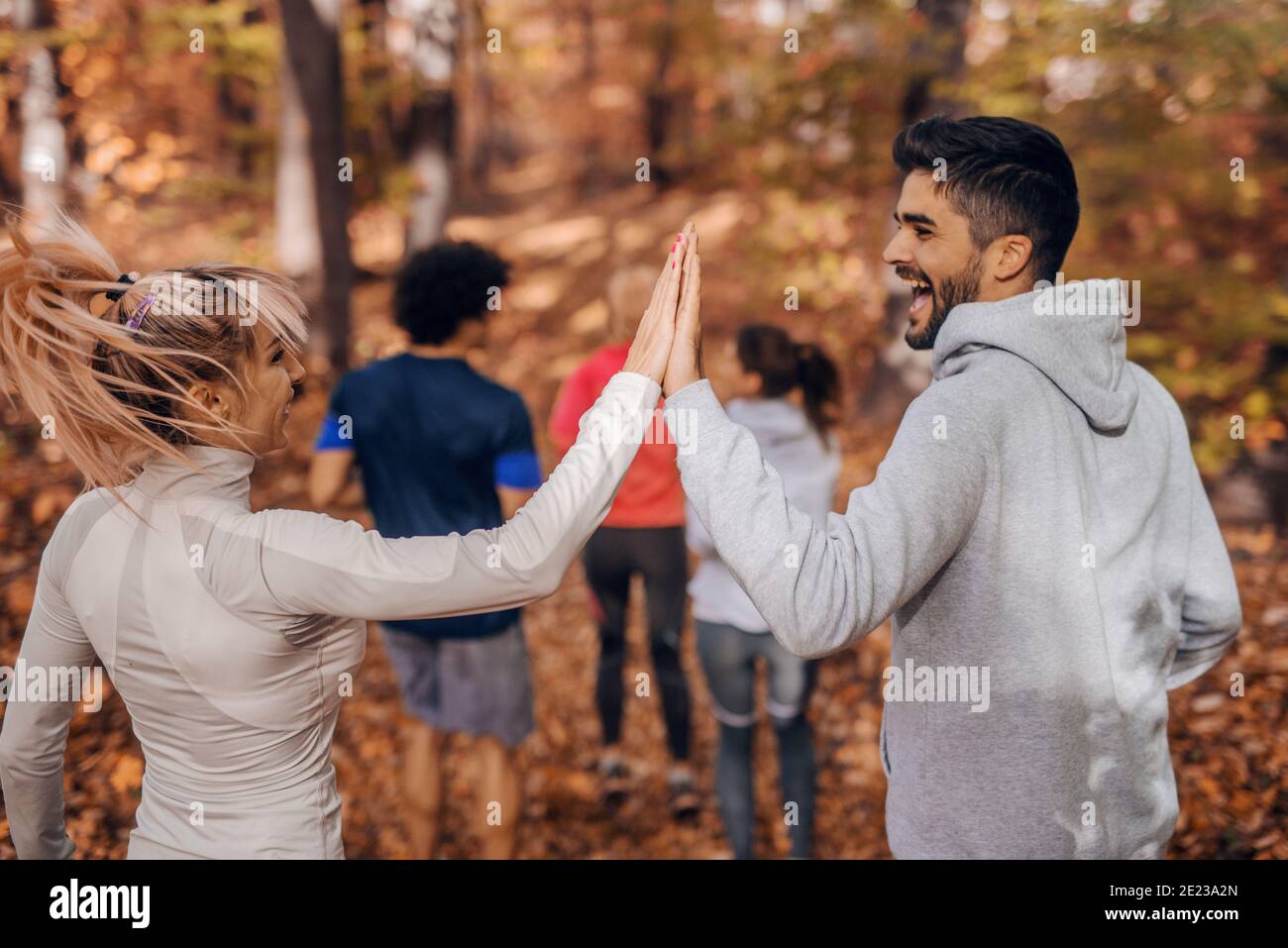 Runners giving high five while running. Forest in autumn exterior ...