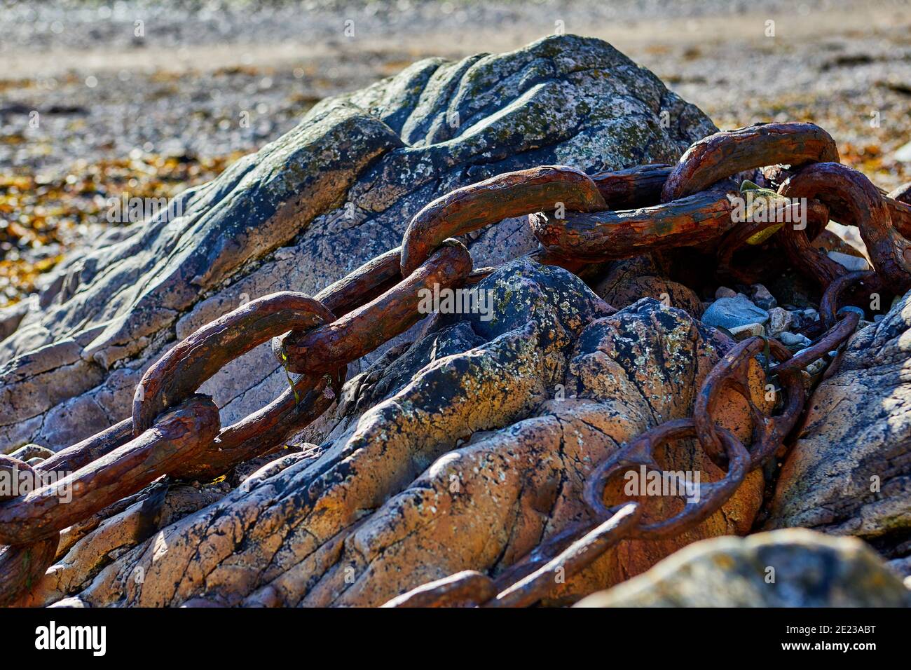 Abstract image of old rusty chains over a granite rock on beach with a ...