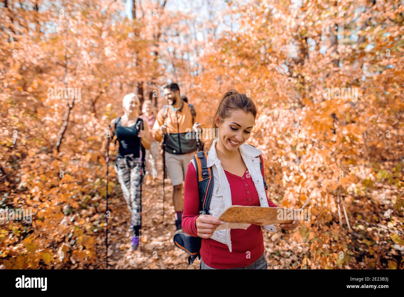 Small happy group of hikers walking in the forest in autumn. Woman ...