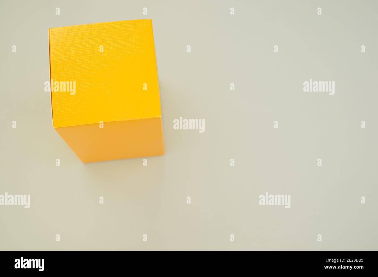 Yellow paper cube isolated on a grey background Stock Photo - Alamy