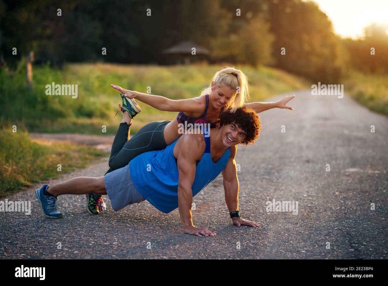 Training together is more fun. Young handsome man doing push ups while ...