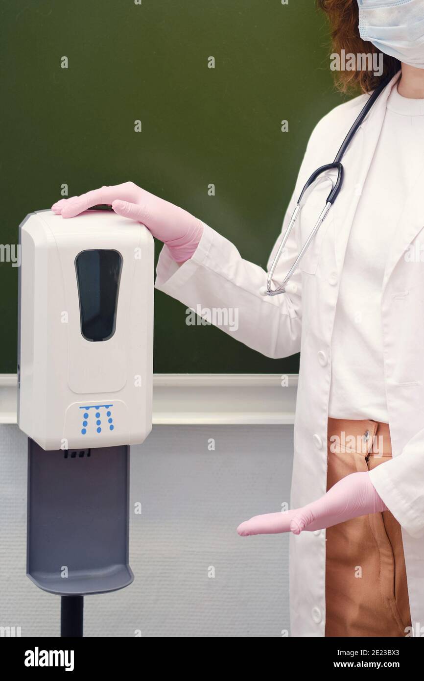 School nurse showing automatic sanitizer dispenser in class. Learning ...