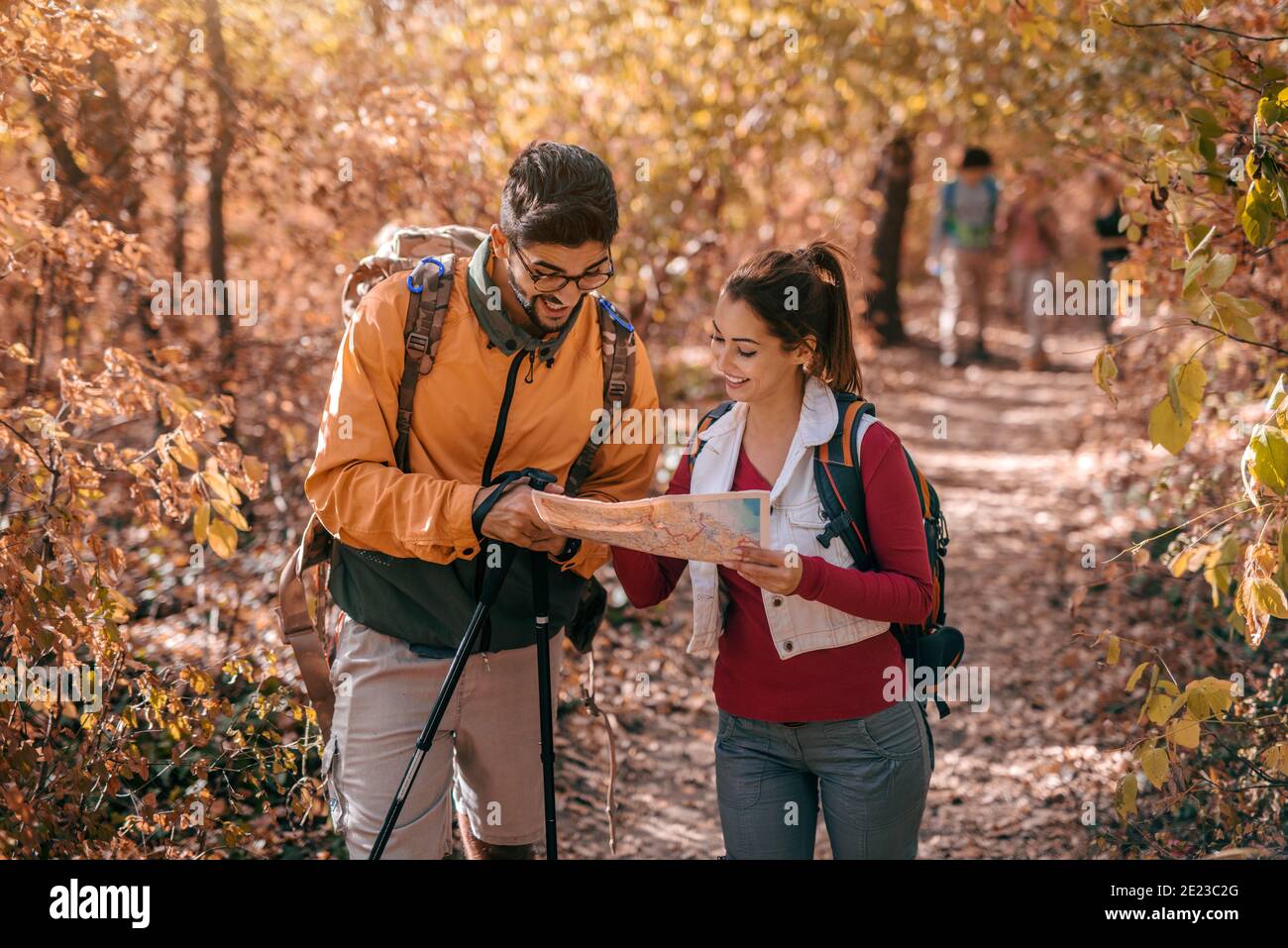 Hikers looking at map while standing in the woods. In background their ...