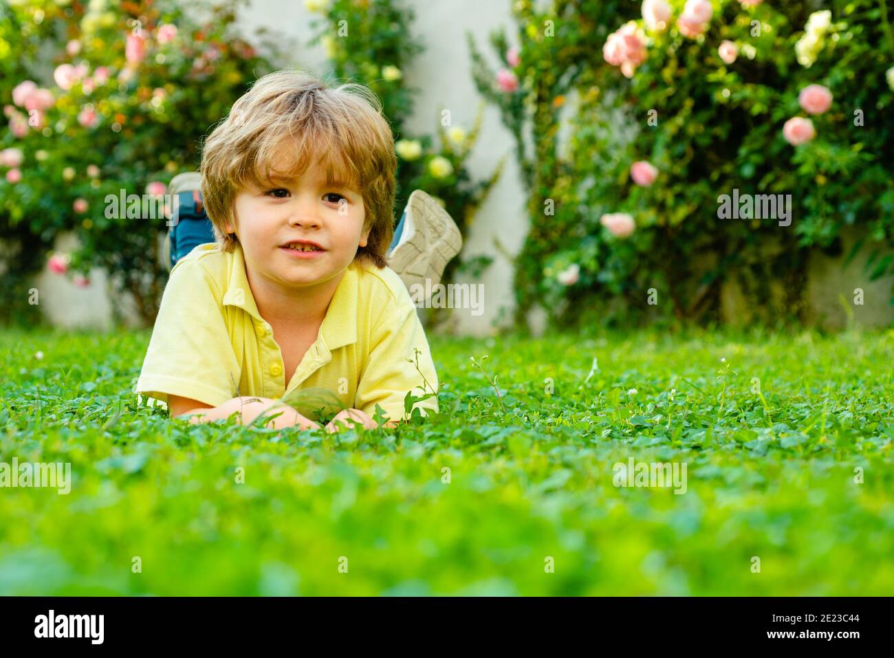Child in park outdoor. Spring kid lying on grass. Summer boy walk ...