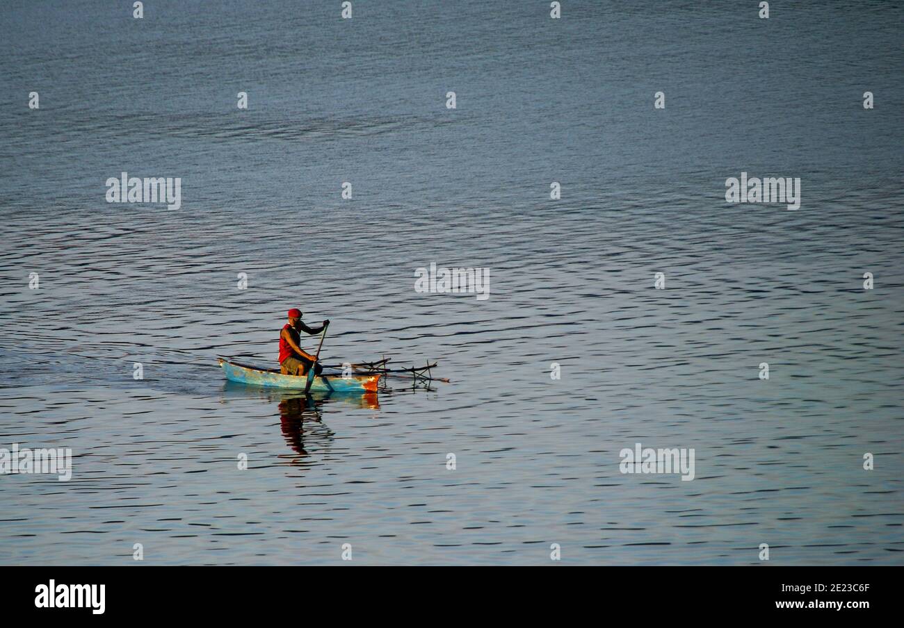A young man paddles a typical wooden dugout canoe in Simpson Harbour ...