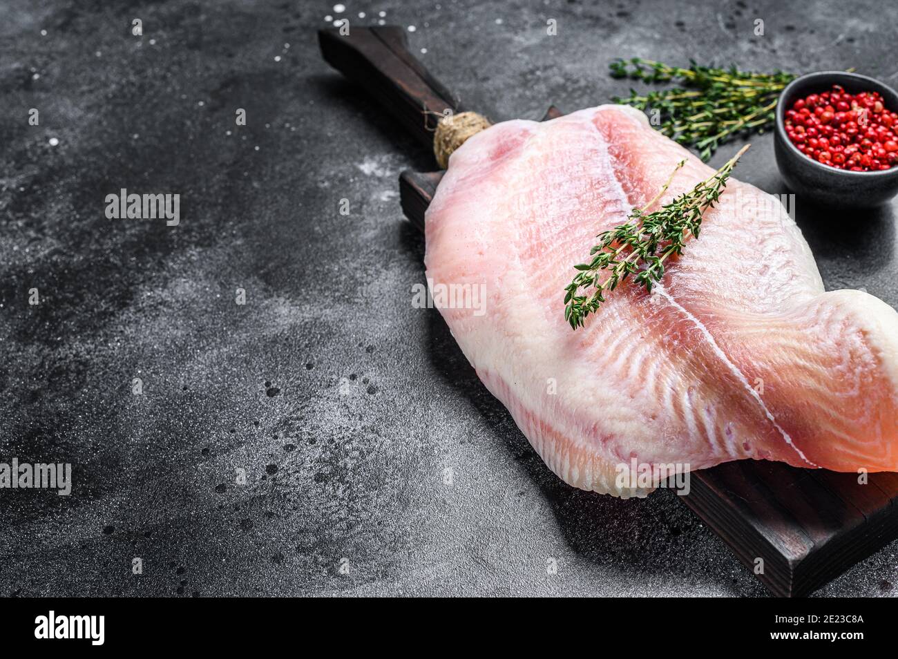 Raw fillet of white fish catfish on a cutting board. Black background ...