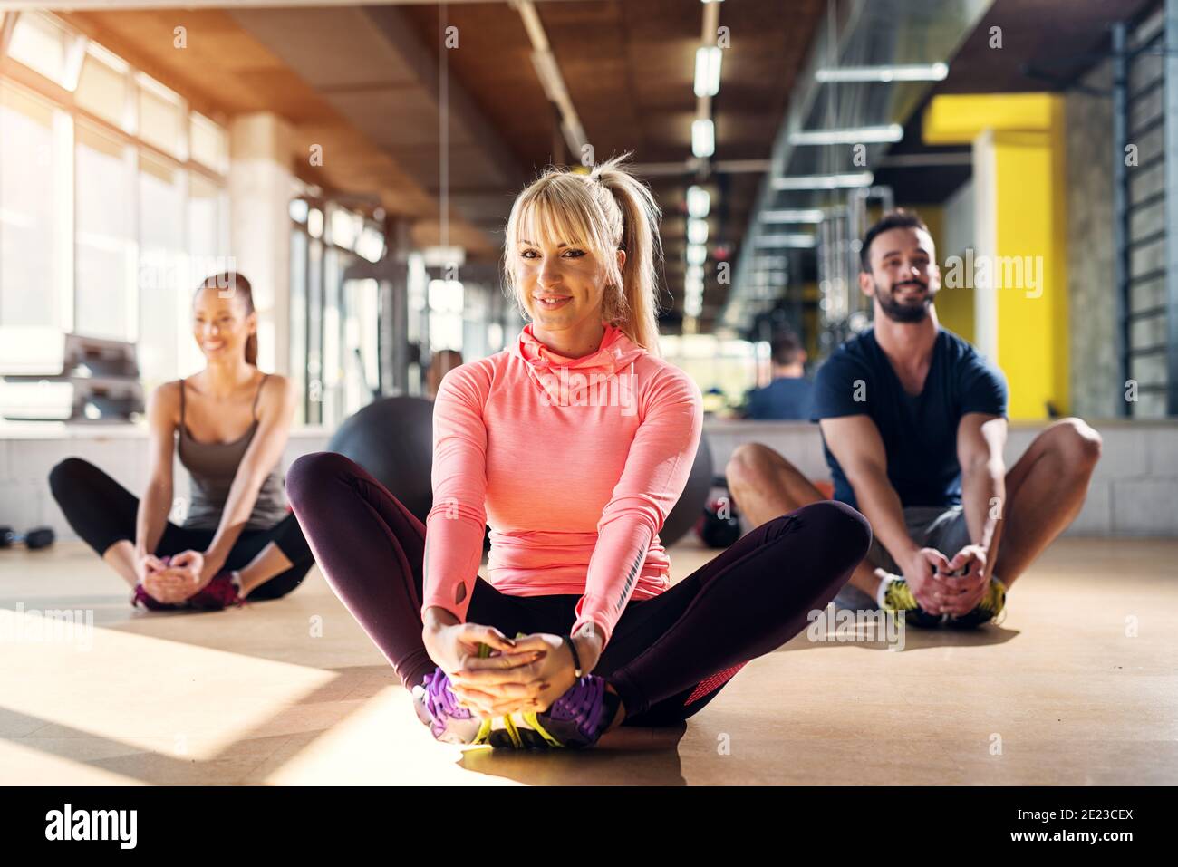 Young tired athletes in a gym stretching their muscles after pilates ...
