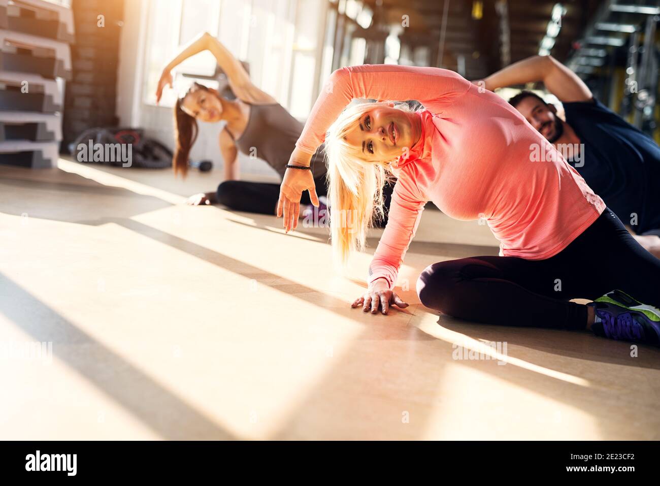 Young tired athletes in a gym stretching their muscles after pilates ...