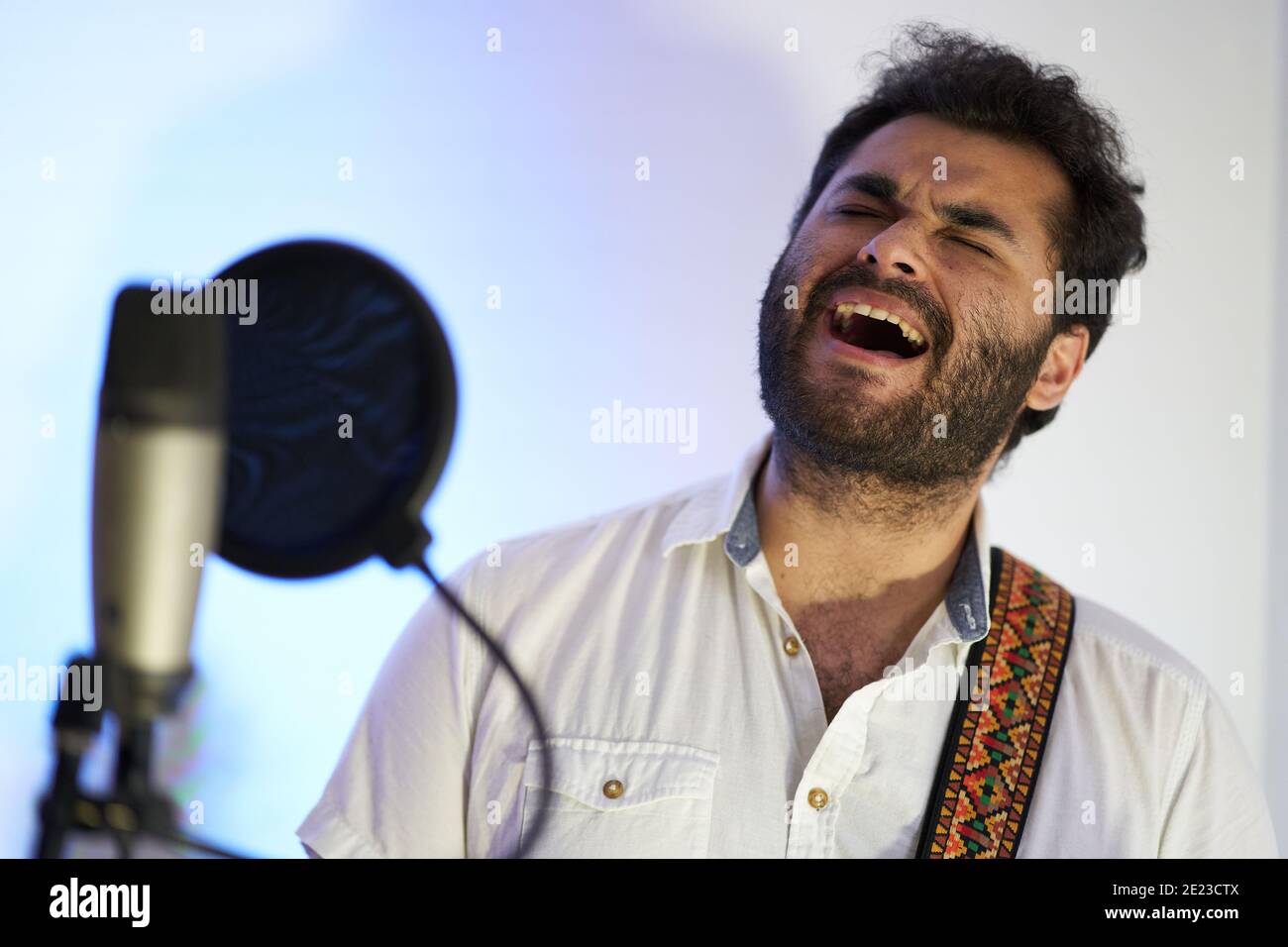 Professional male musician with electric guitar singing ...
