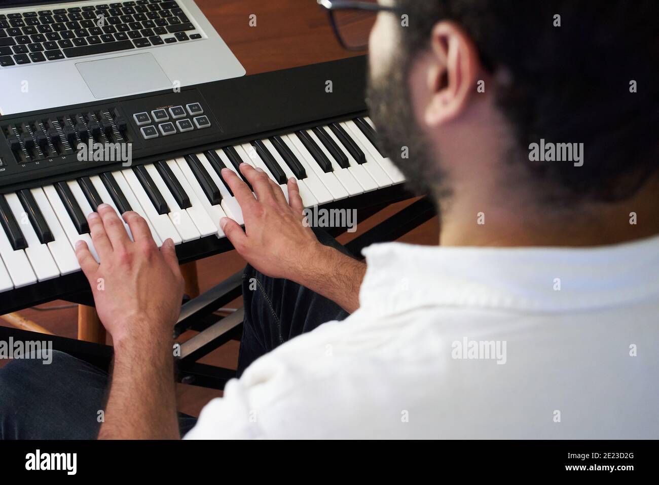 High angle back view of male musician hands playing on electronic piano ...