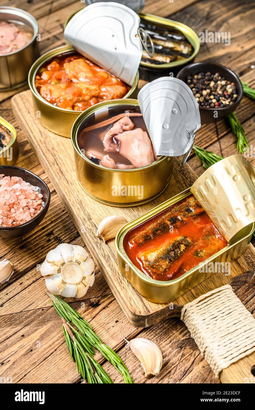 Various canned fish and seafood in a metal cans. Wooden background. Top ...