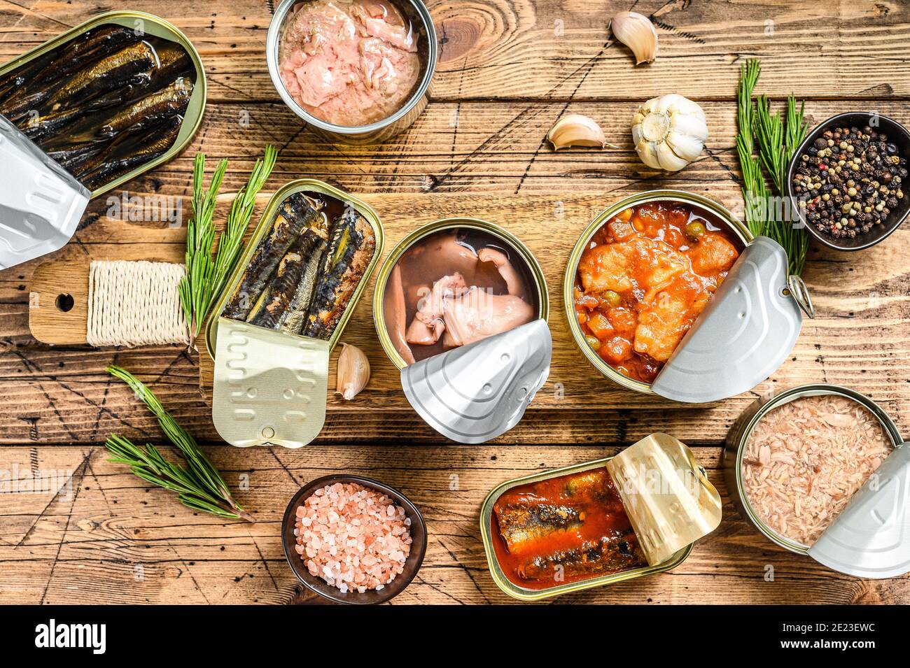 Various canned fish and seafood in a metal cans. Wooden background. Top ...