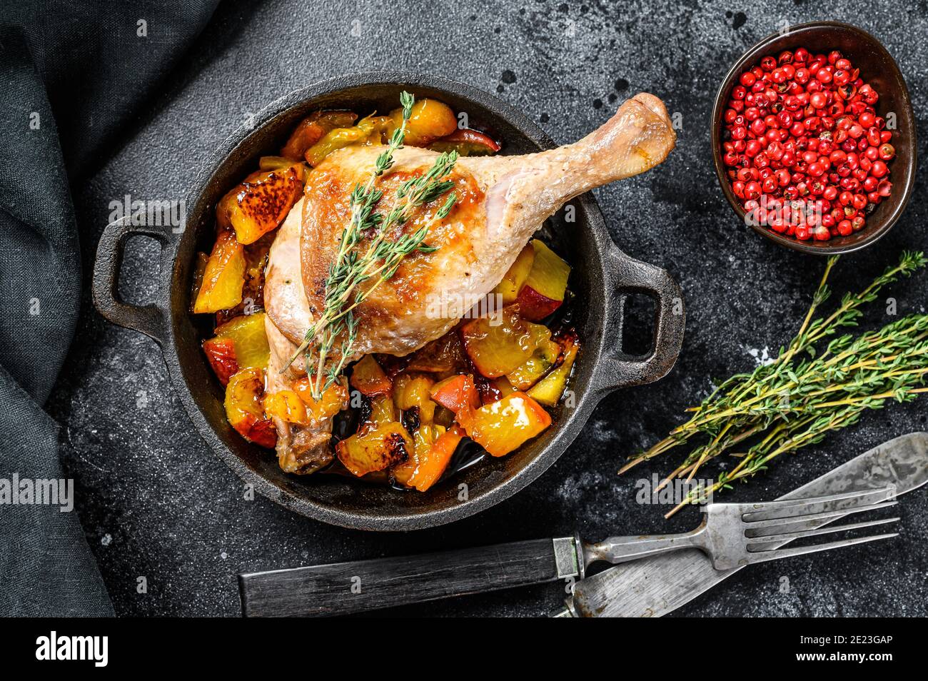 Oven-baked duck legs with figs and peachs. Black background. Top view ...