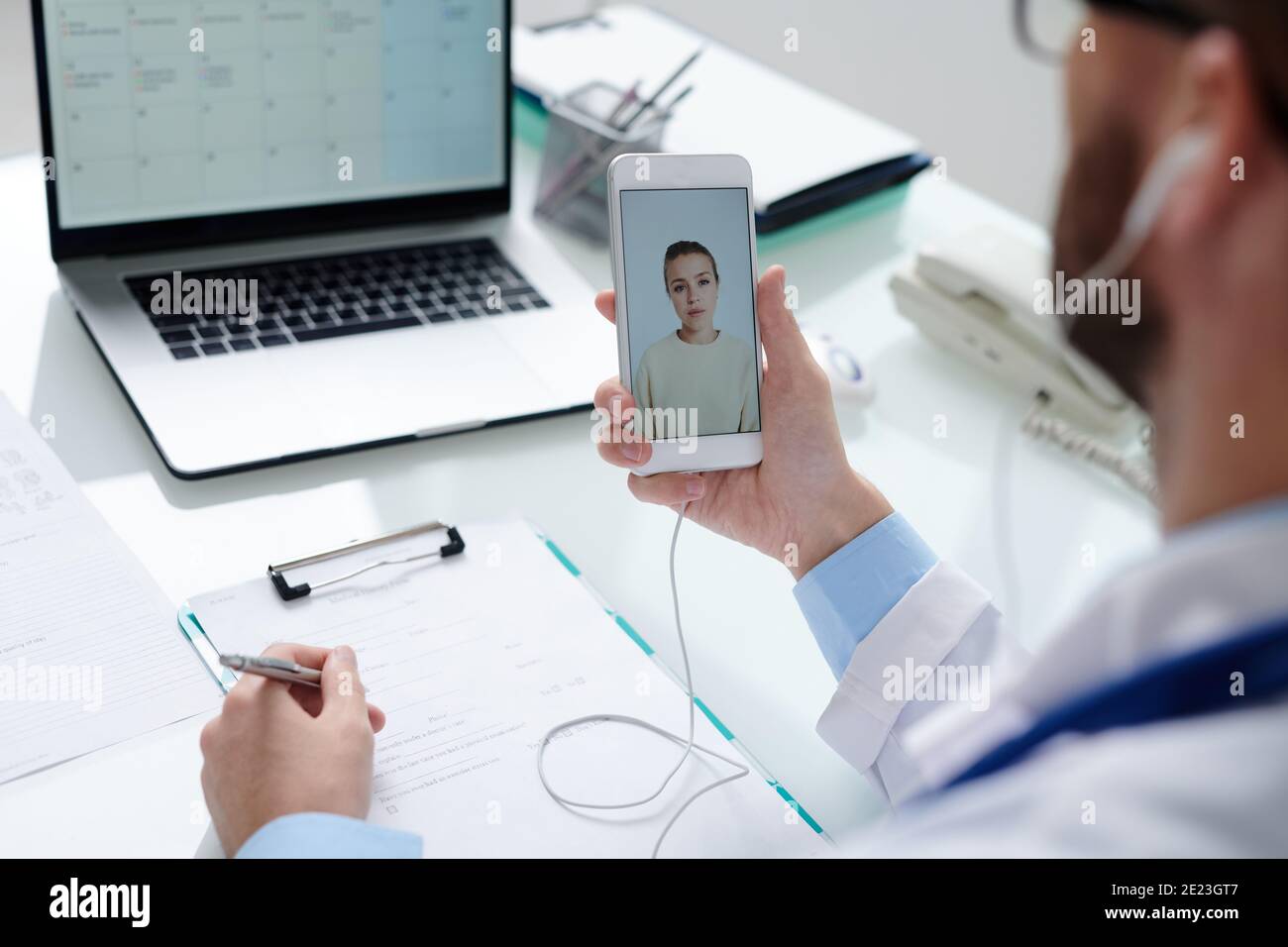 Young female patient on smartphone screen looking at doctor with ...