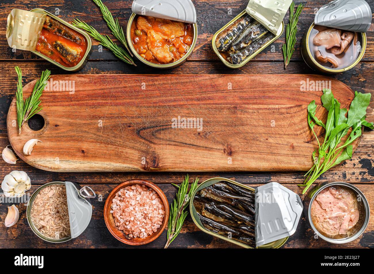 Various canned fish and seafood in a metal cans. Dark Wooden background ...