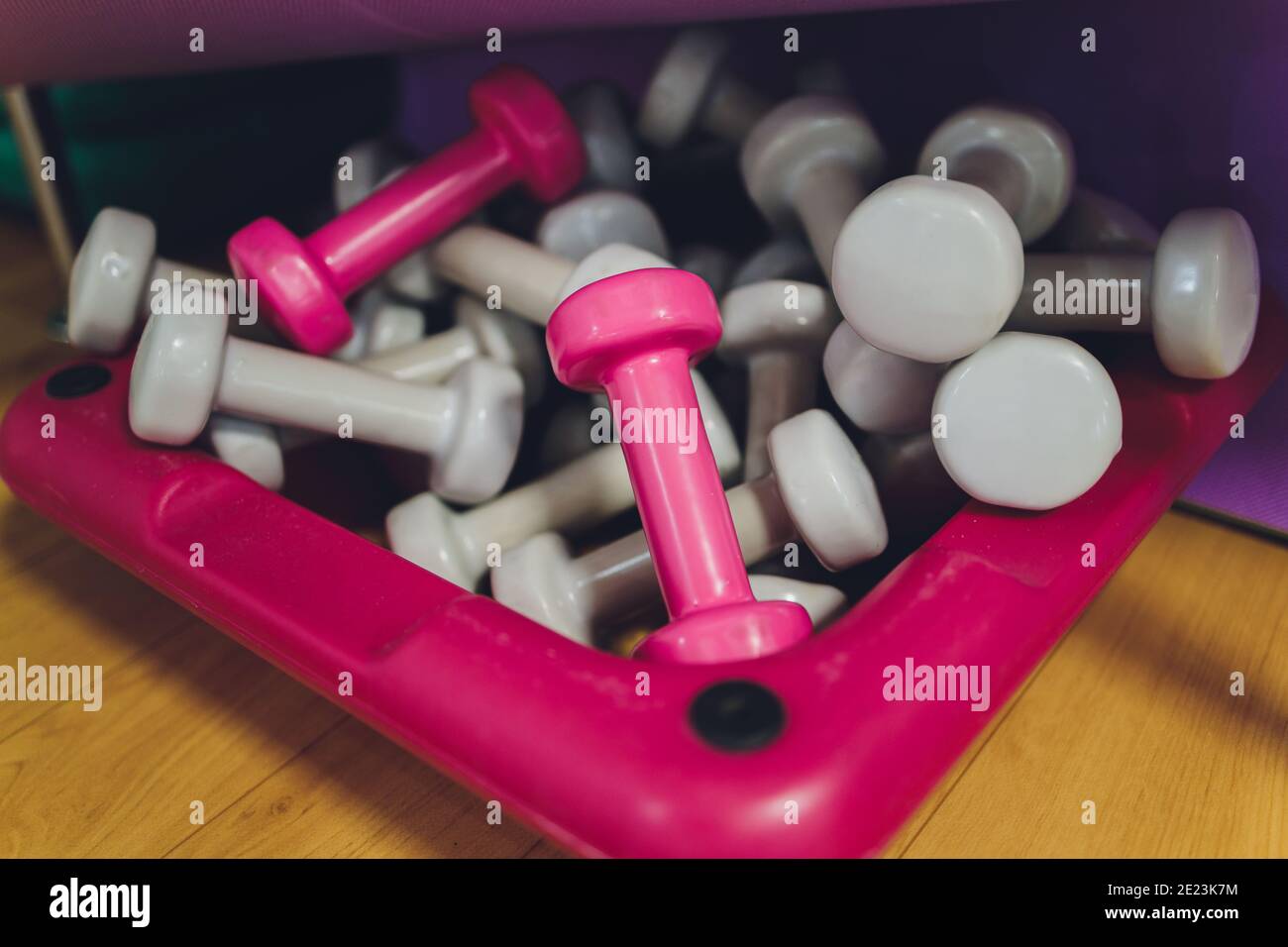 Bright pink, green, red and yellow small dumbbells on a black background. Sport concept Stock ...