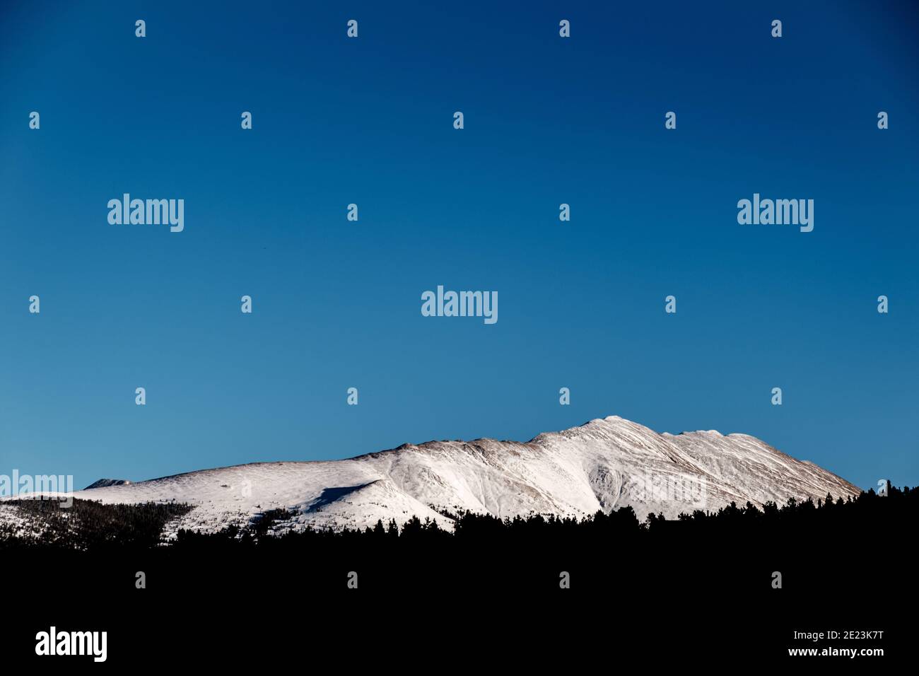 Landscape of hills covered in the snow under a blue sky and sunlight ...