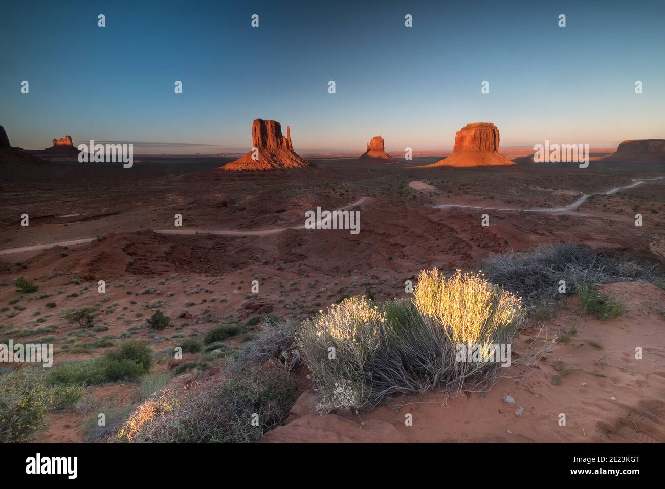 Sunset over the three classic buttes with roads and some vegetation ...