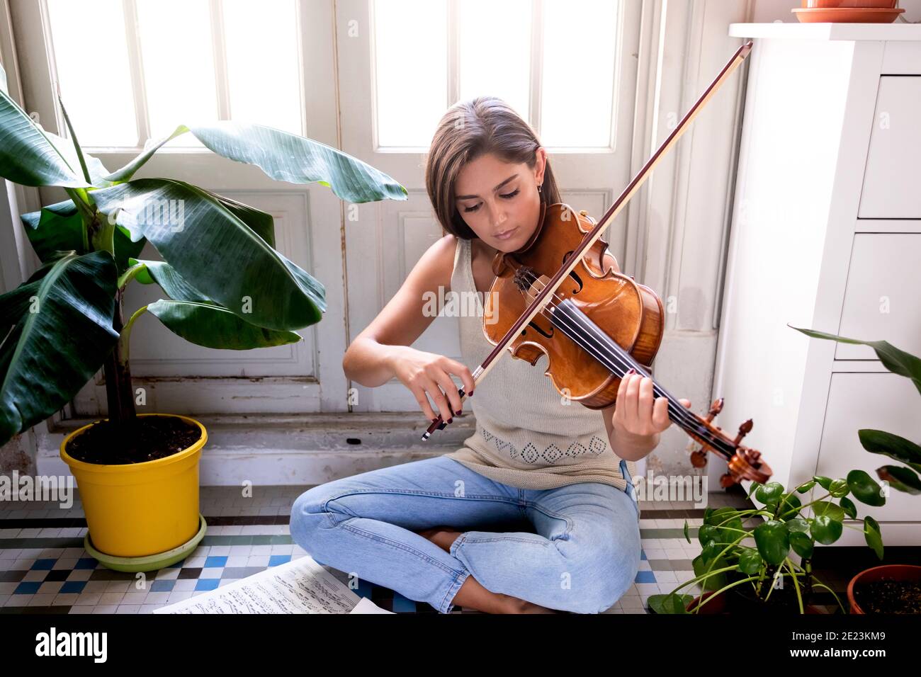 Young girl musician playing the viola sitting on the floor Stock Photo ...