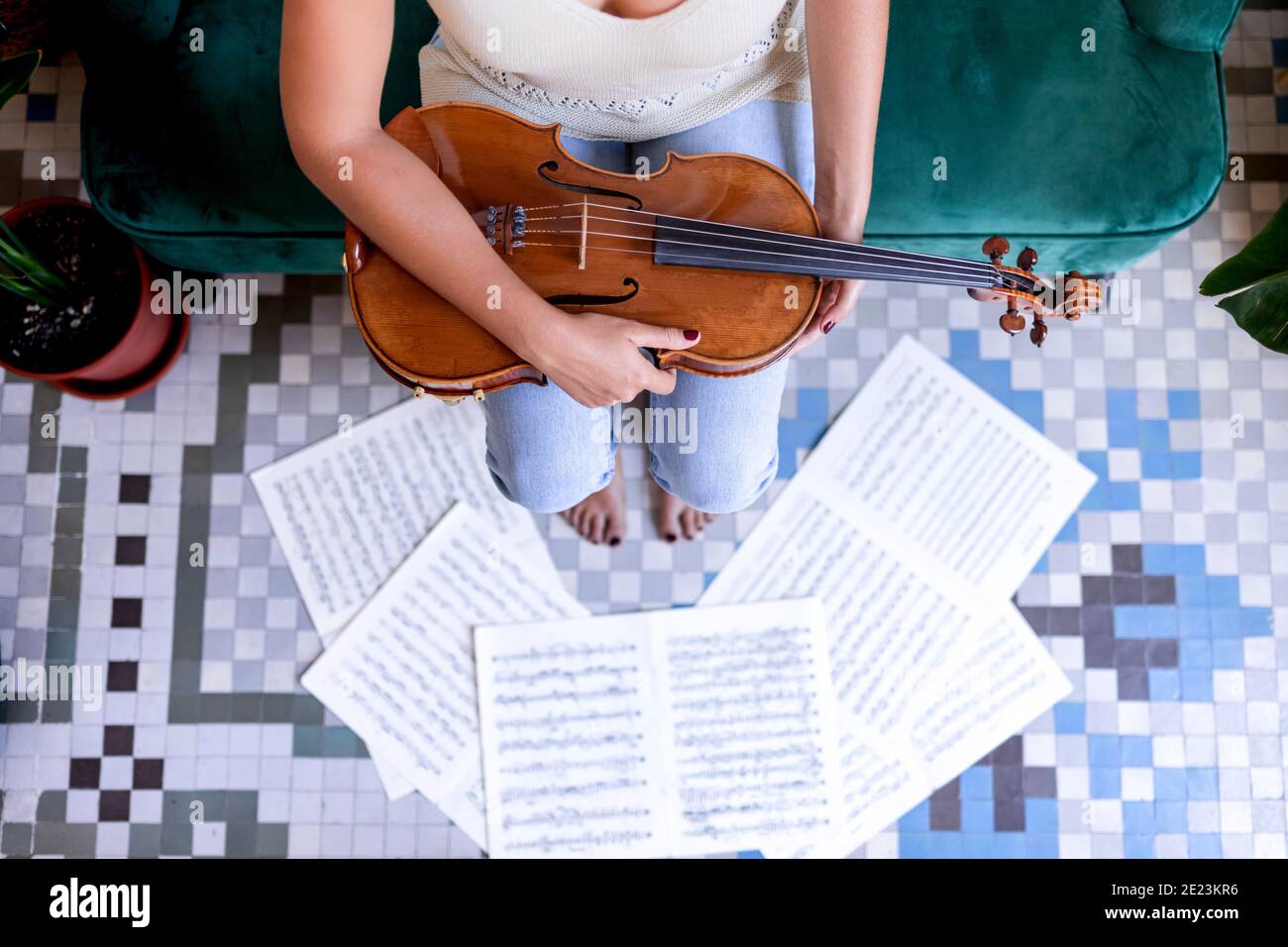 Sitting girl holding a viola, sheet music surrounding her bare feet ...