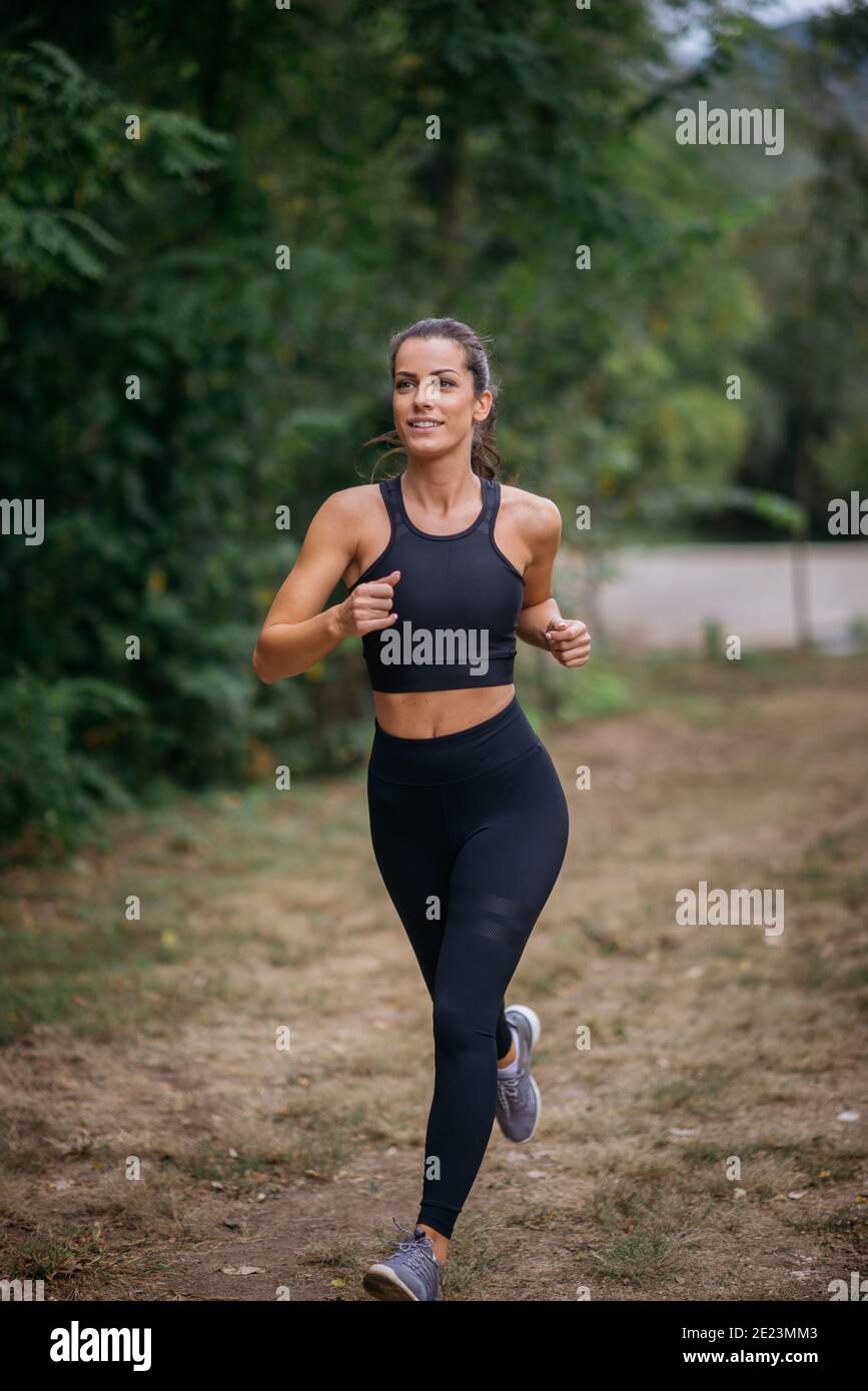Young sportswoman running on park during outdoor workout Stock Photo ...