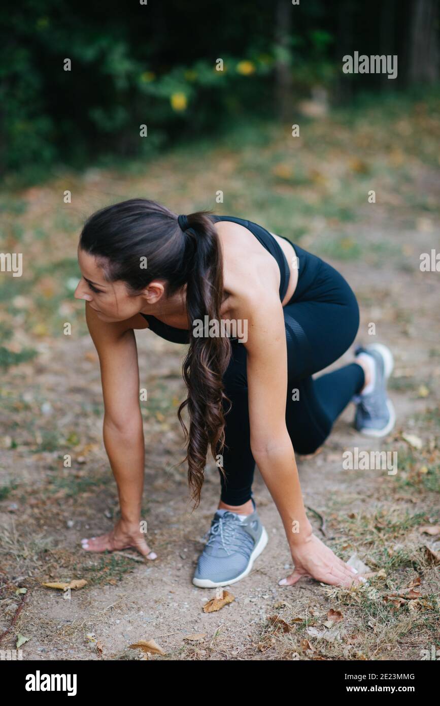 Athletic woman crouching starting position to run in nature Stock Photo ...