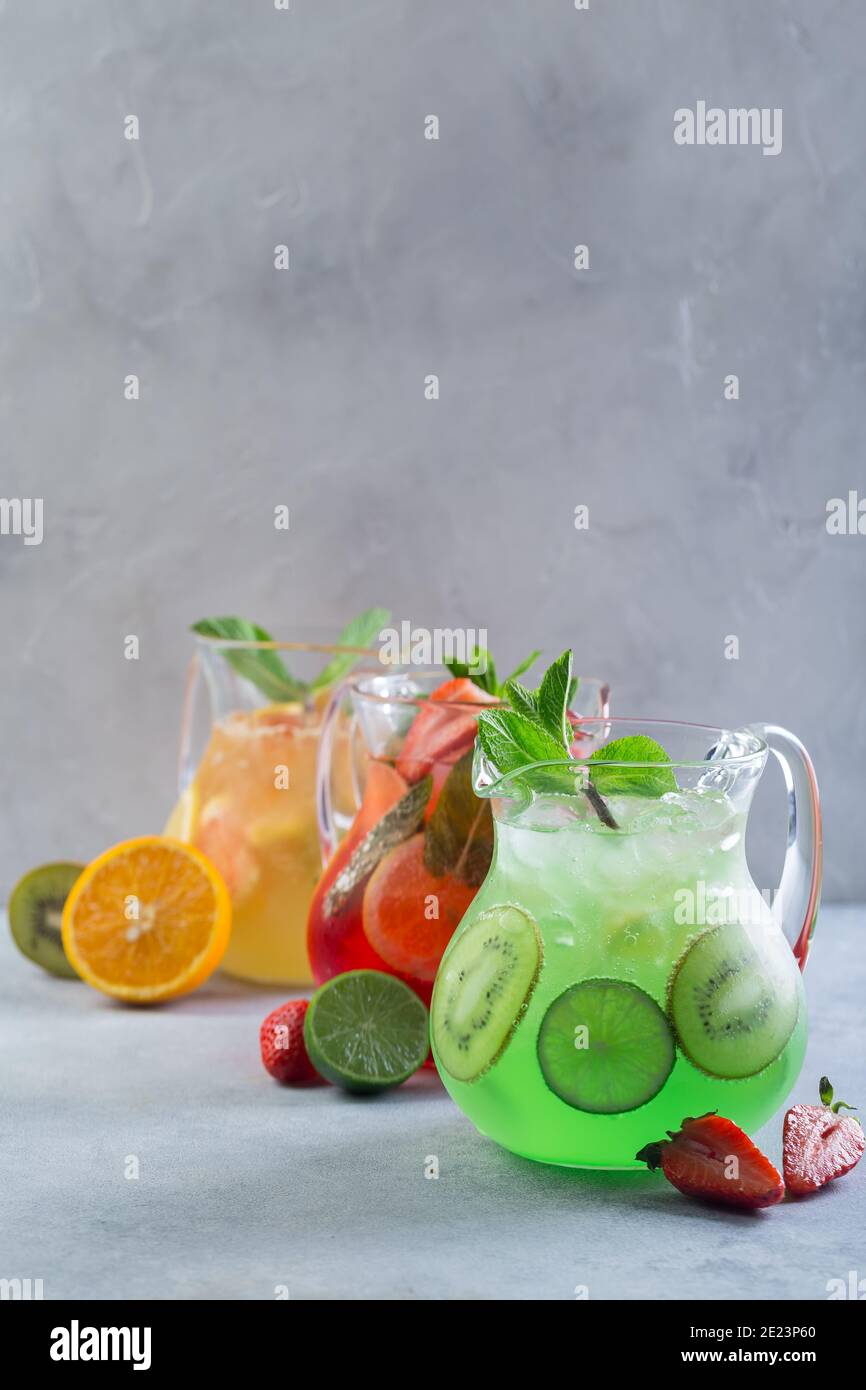 Different color lemonade in glass decanters with fruits and garnished ...