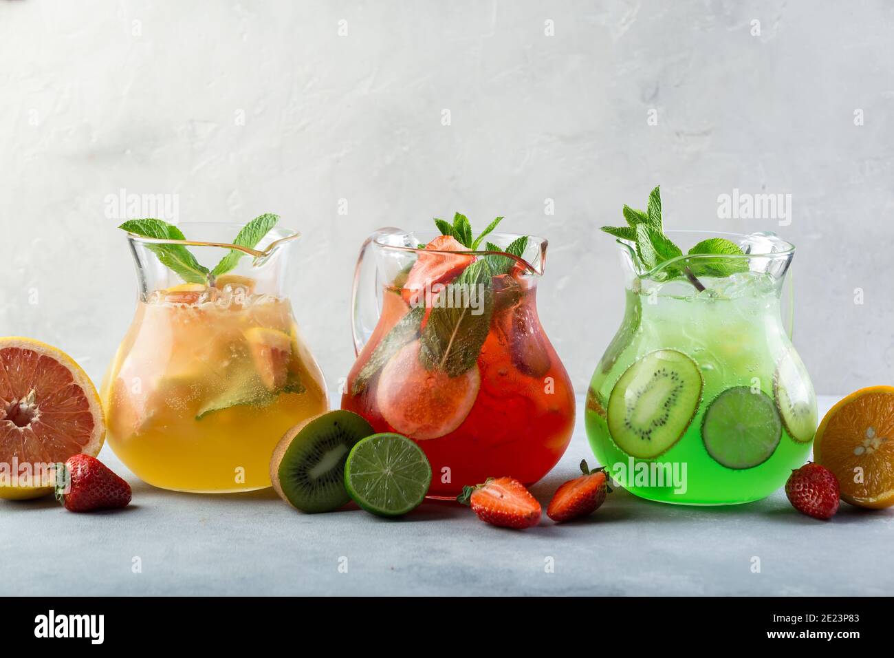 Different color lemonade in glass decanters with fruits and garnished ...