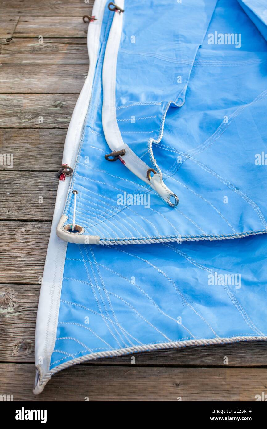 A blue jib sail rolled up on the dock with shows a close up of the bolt ...