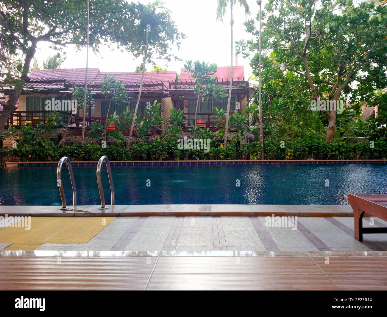 Poolside view with tropical plants and bungalow buildings Stock Photo ...
