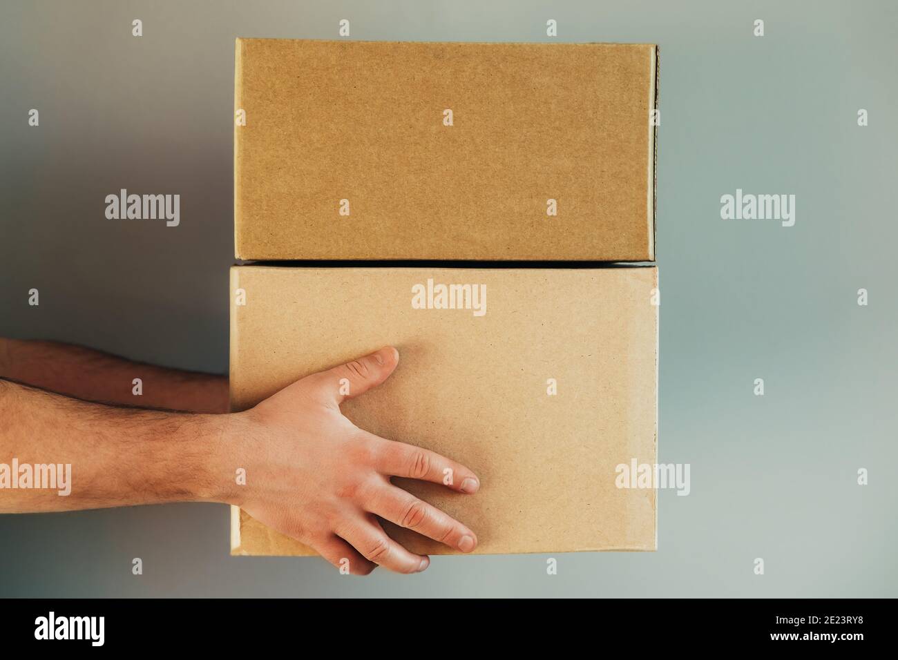The hands of delivery service man delivers carton boxes on the grey ...