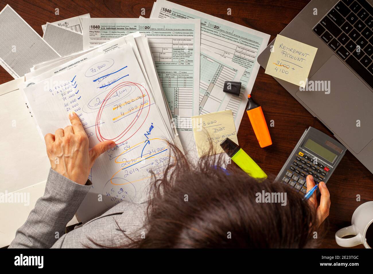 A woman is preparing her tax return in her office using forms ...