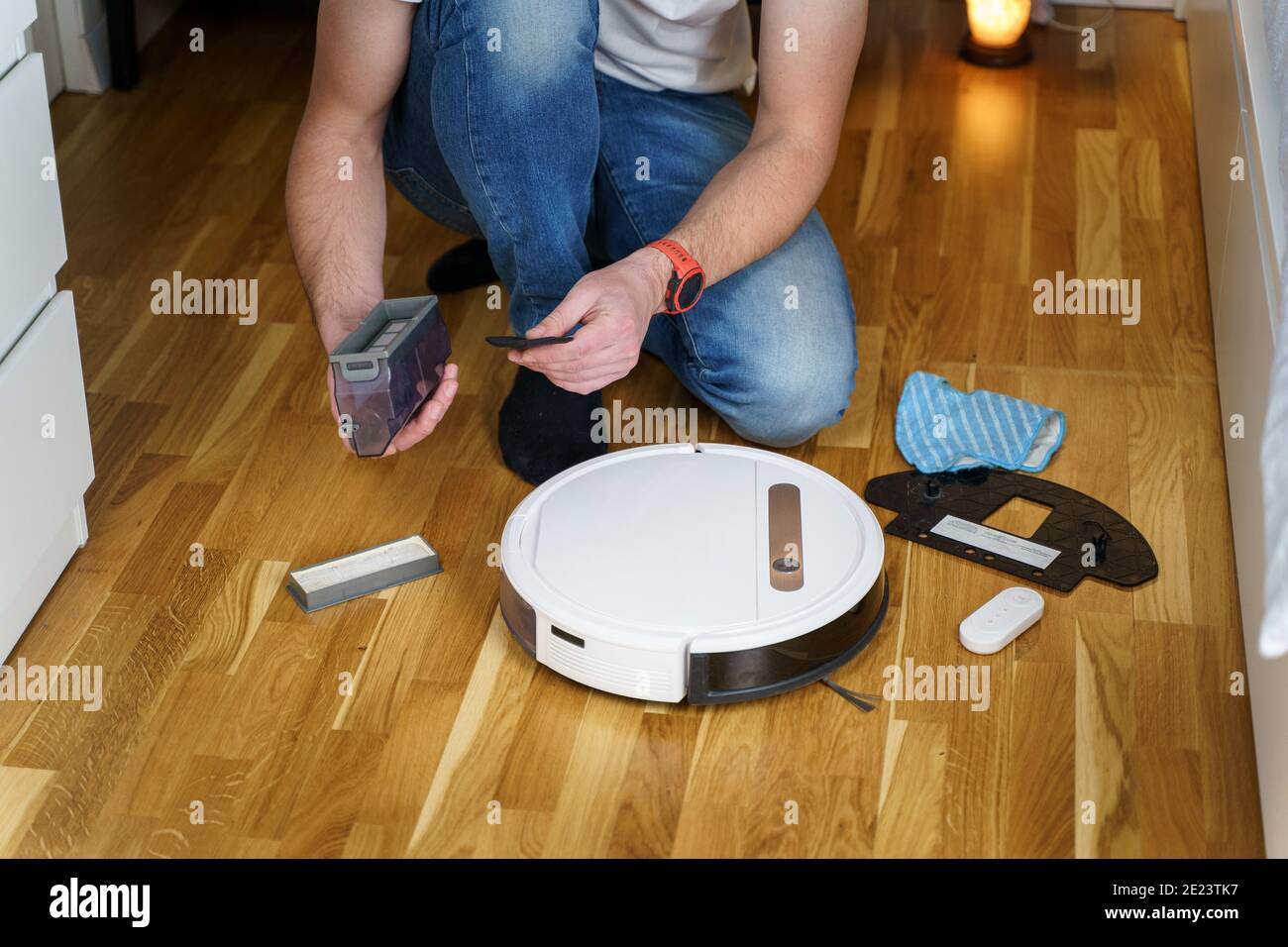 Caucasian young man doing white robot vacuum cleaner maintenance ...