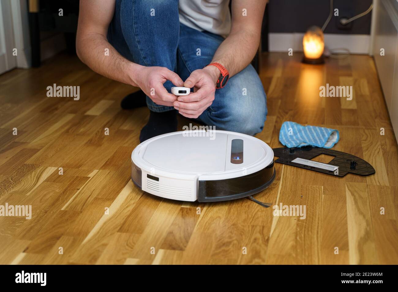 Caucasian young man doing white robot vacuum cleaner maintenance ...