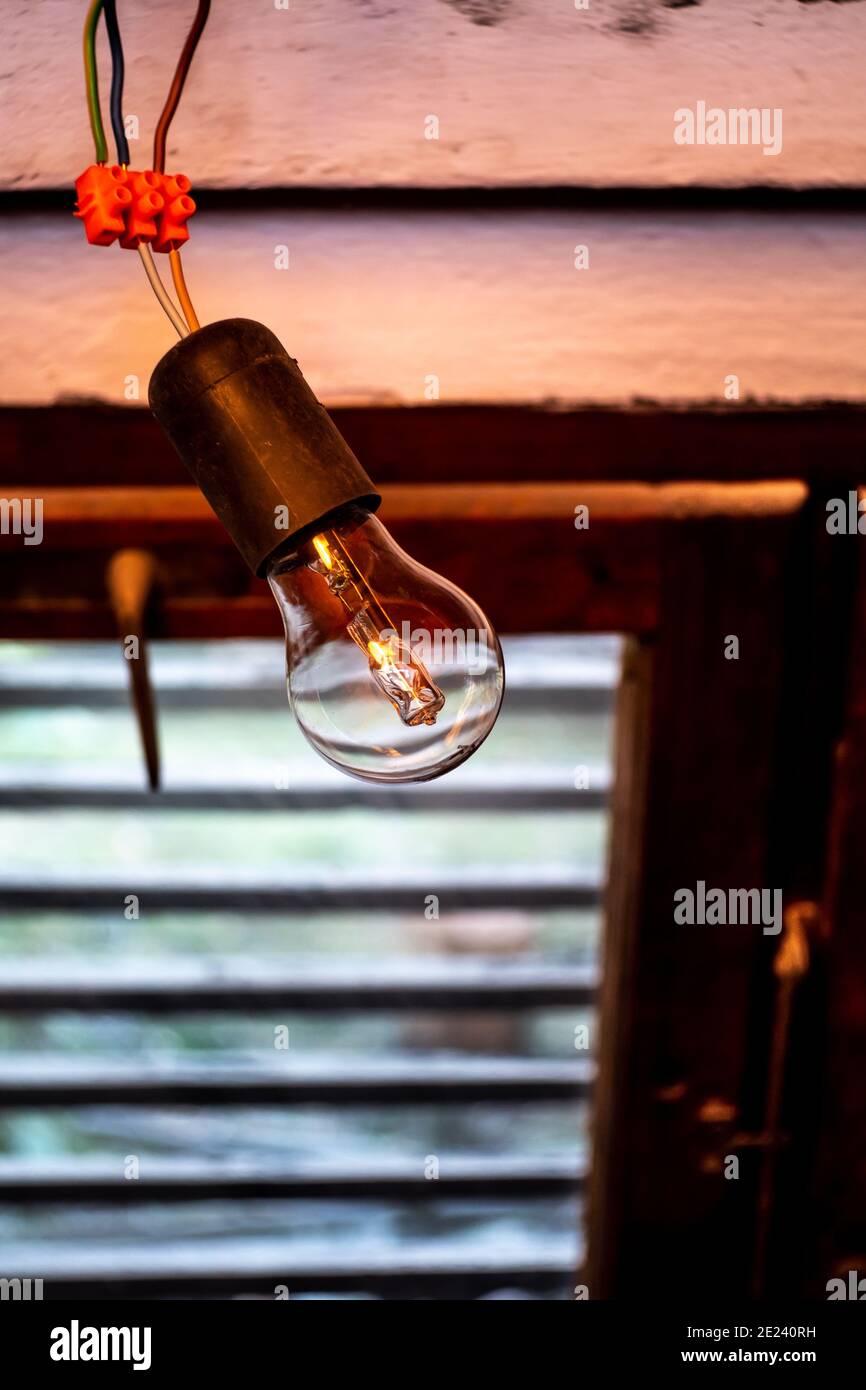 Vertical shot of a light bulb hanging from wires on a wall with a ...