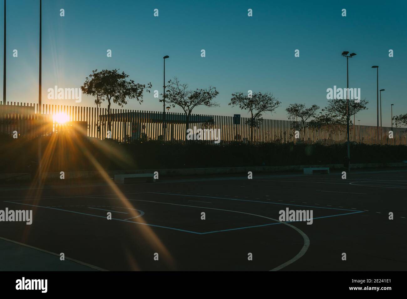 Flaring sun in an outdoor basketball court in a public park during ...