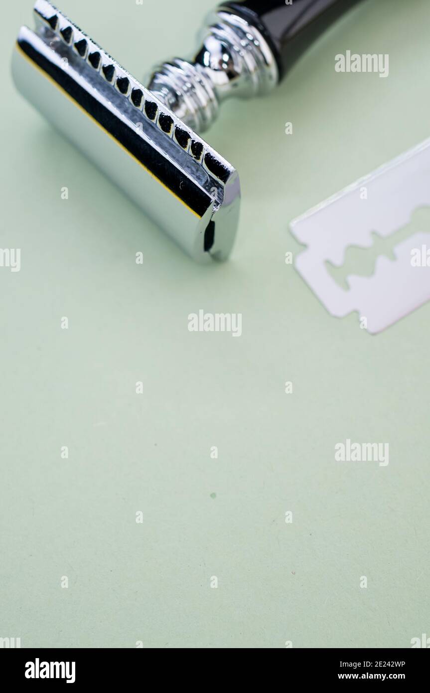 Vertical shot of a mechanical razor and blade isolated on light green ...