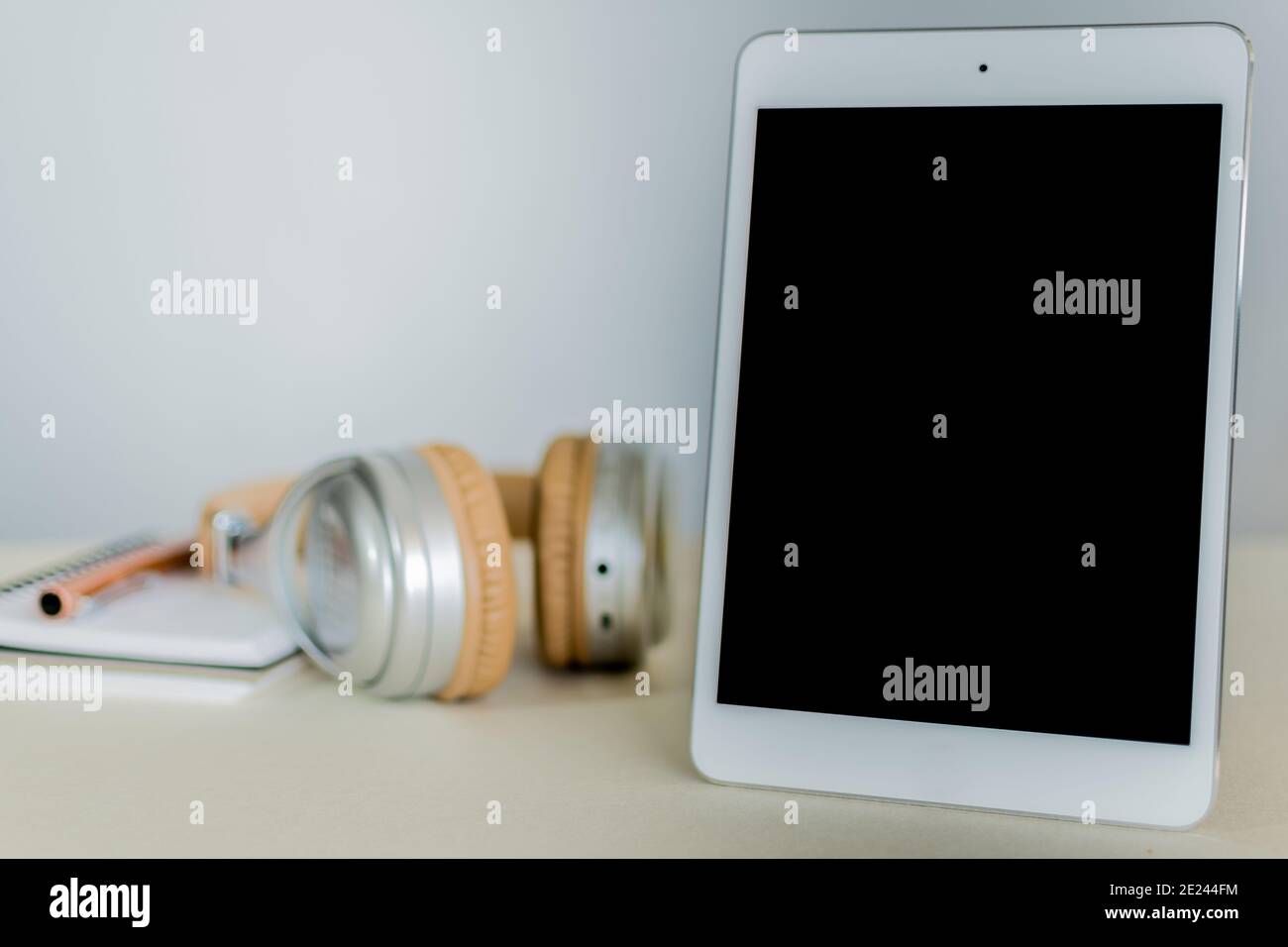 Tablet with black screen next to wireless headphones on desk ...